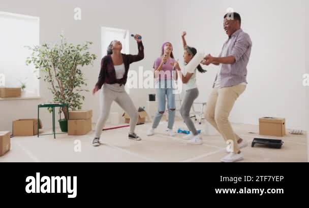 Crazy happy family dances in middle of room during break from painting ...