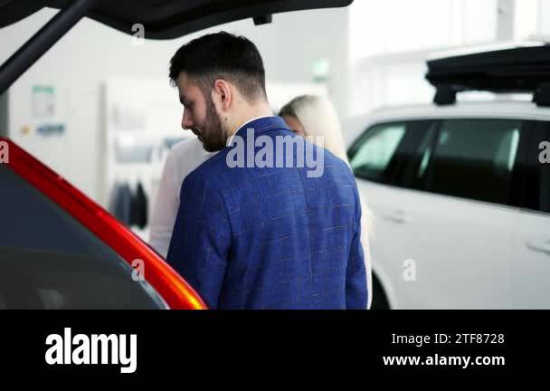 Salesman showing trunk from inside to customers in automotive ...