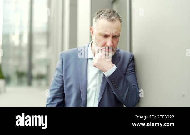 Sad confused mature businessman standing near office building outside ...