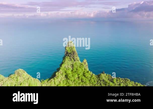 Drone flying around beautiful green peak covered with fresh tropical ...
