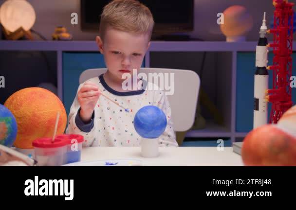 Blond boy paint planet solar system Pluto with colorful paint sitting ...