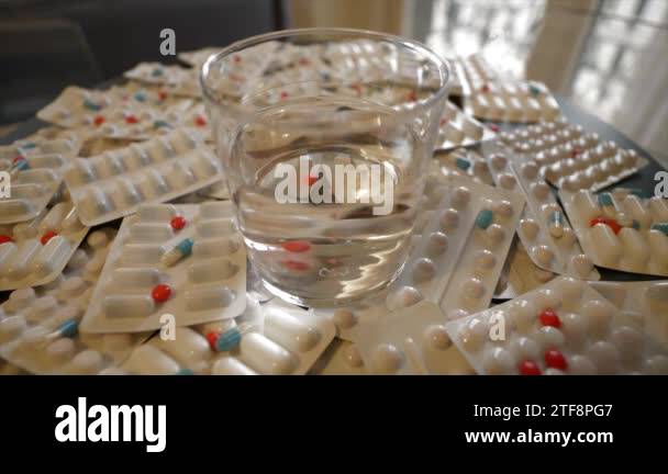 8K 7680x4320.Medicine pills in the glass.Red drugs melting in water ...