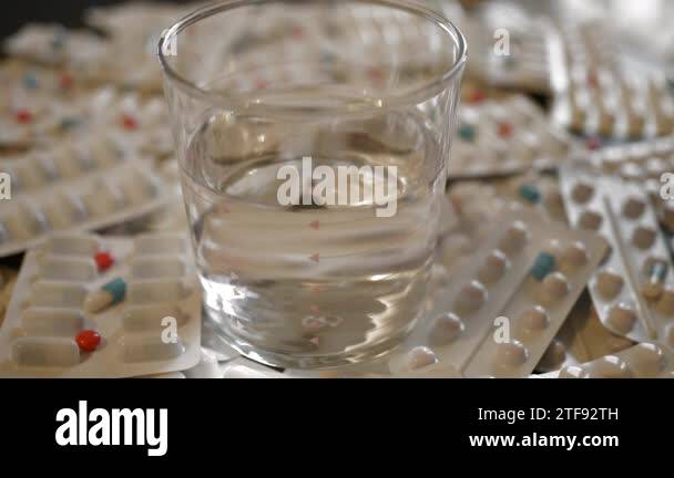 8K 7680x4320.Medicine pills in the glass.Red drugs melting in water ...