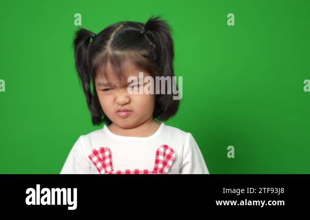 Portrait of Asian angry and sad little girl on green screen background ...