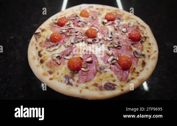 Whole fresh round pizza with tomatoes and mozzarella cheese turns on a ...