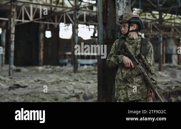 Concentrated female soldier with sniper rifle standing on abandoned ...