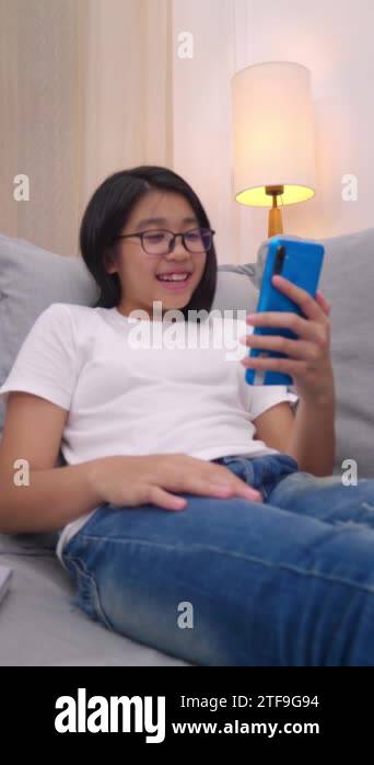 Happy Asian girl sitting on sofa in living room speak with parent on ...