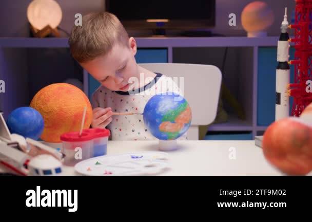Blond boy paint planet solar system Earth with colorful paint sitting ...
