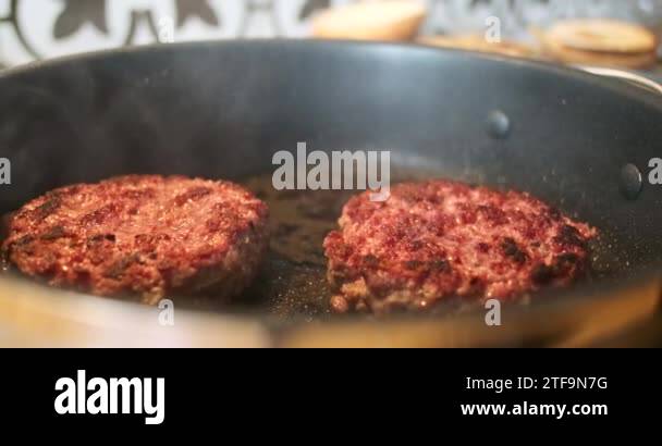 Ready two burger patties in a frying pan. Smoke, close-up, well-roasted ...