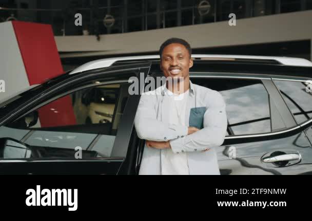 African american car dealership principal standing in vehicle showroom ...