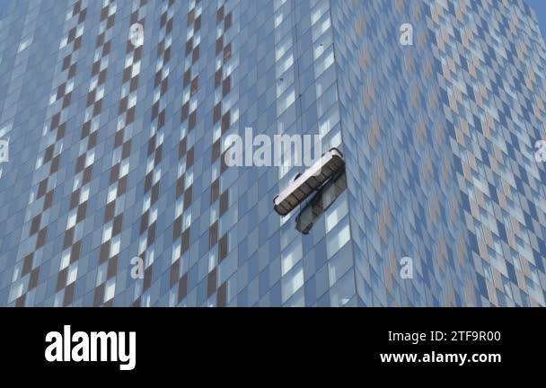 Two workers, window cleaners on suspended scaffold platform moving up ...