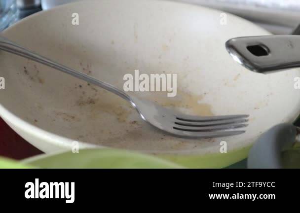 The kitchen utensils in the wash basin need to be washed. A pile of ...