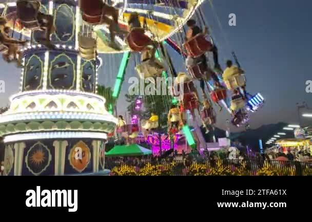People riding on spinning swing carousel in amusement park.Swing rides ...