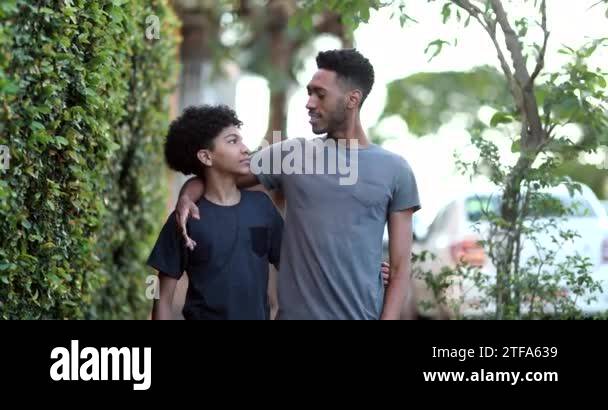 Two brothers walking together in sidewalk. Black brother giving advice ...