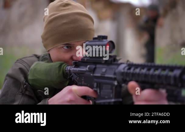 Portrait of concentrated man shooting with gun in slow motion as ...