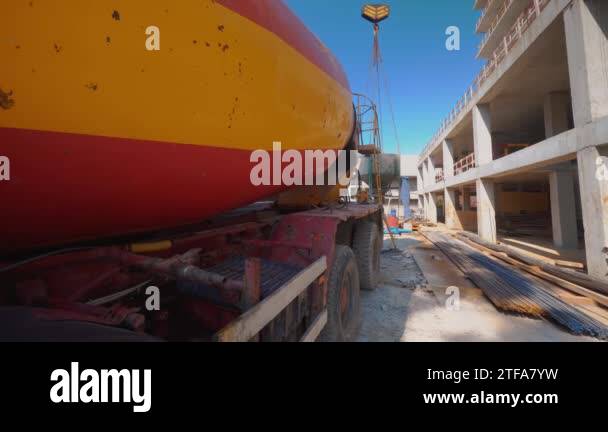 concrete mixer stands on construction site. Crane lifts container ...