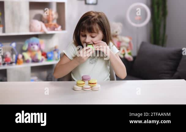 Attractive scholl girl bites a macaroon, surprised with taste ...
