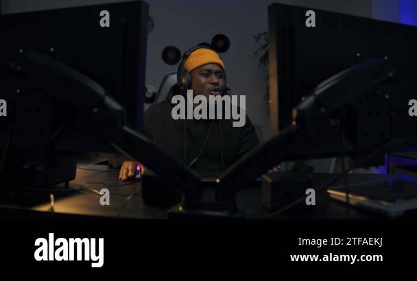 Dark room at night lit by led lights. Guy wearing cap headphones is ...