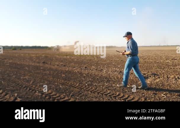 potato harvesting. farmer, holding a digital tablet in his hands, walks ...