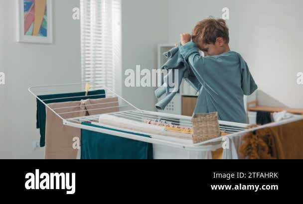 A hardworking little smiling boy helps his mom in the laundry room with ...
