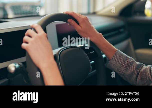 Womans hands on steering wheel of vehicle of electric car. Close up shot. Dashboards design The ...