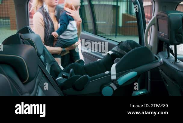 Camera inside the car Mother carries baby boy in arms She opens the ...