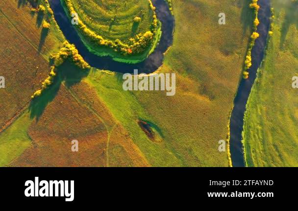 Top down view on exotic winding river flows through green meadows ...