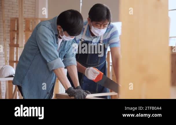 Asian man carpenter training showing apprentice how to use hand sawing ...