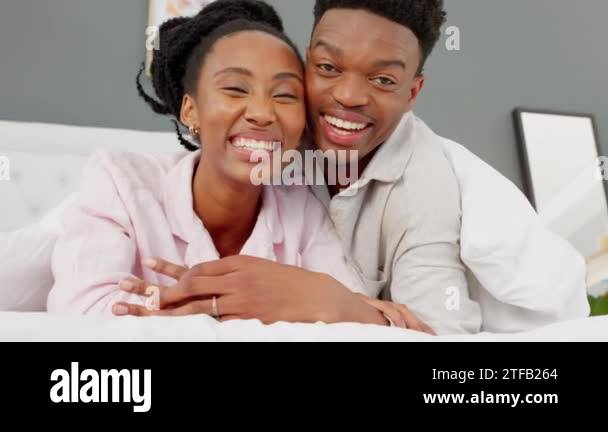 Happy black couple having fun in bed, hug and bonding in a bedroom. Portrait of a caring husband ...