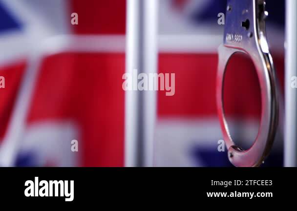 Handcuffs swing on prison bars with Union jack British flag background ...