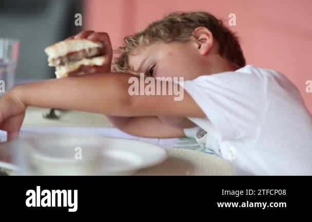 Cute baby boy eating hamburger. Blonde boy child takes a bite of burger ...