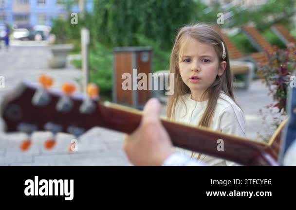 Portrait of serious pretty little girl singing to the accompaniment of ...