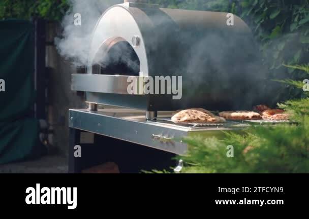 BBQ smoker with long chimney tube and rising smoke outdoor, firing up ...