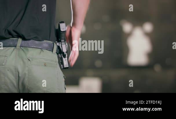 Back view close-up of a man pulling a pistol out of its holster and ...