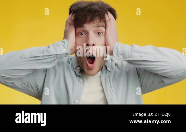Unbelievable. Young amazed guy shouting and grabbing head in amazement ...