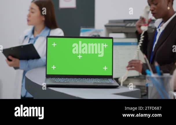 Laptop with greenscreen template on hospital reception counter. Medical ...