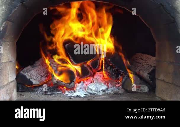 There is a fire blazing in the wood-fired traditional pizza oven with ...