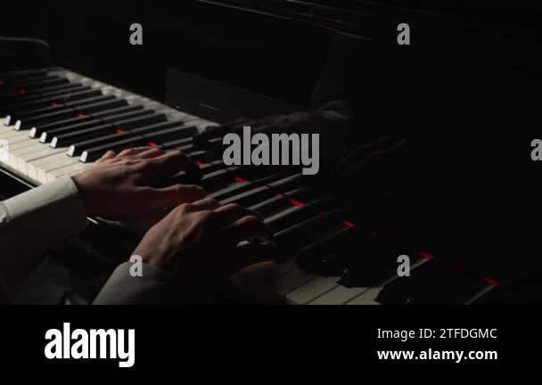 Talented pianist plays classical melody on piano in dark. Mans hands ...