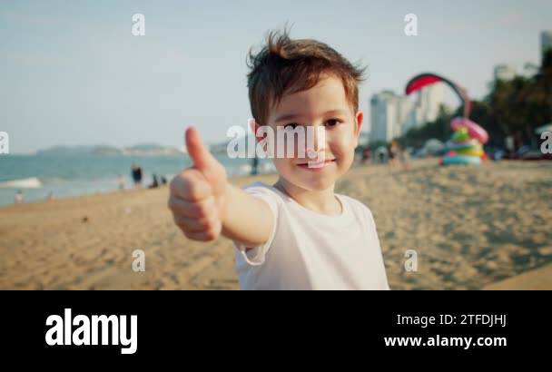 Cute child shows thumbs up gesture, happy facial expression emotion ...