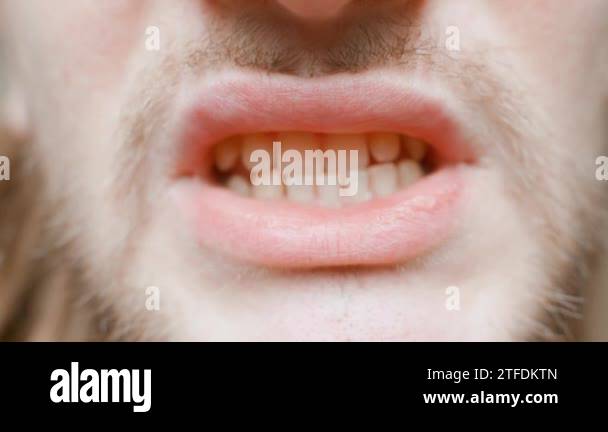 A young guy shows his lips close up. Guy with long hair, mustache and ...