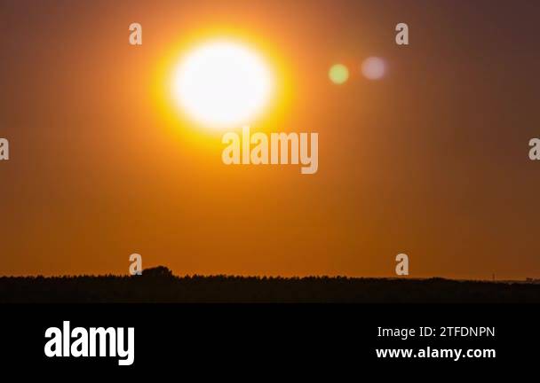 Time lapse bright orange sunset sun sets behind the clouds. The end of ...