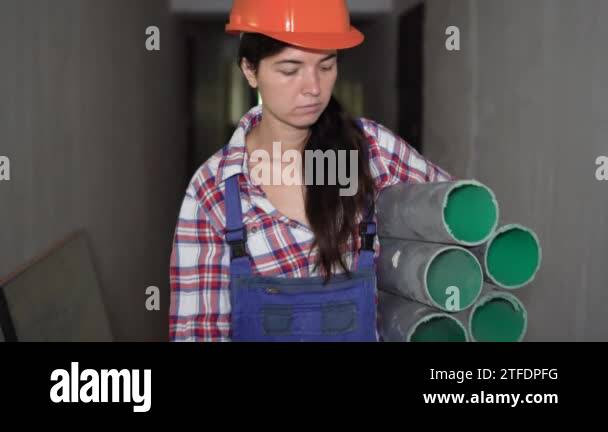 Female construction worker carrying water pvc pipe working in ...