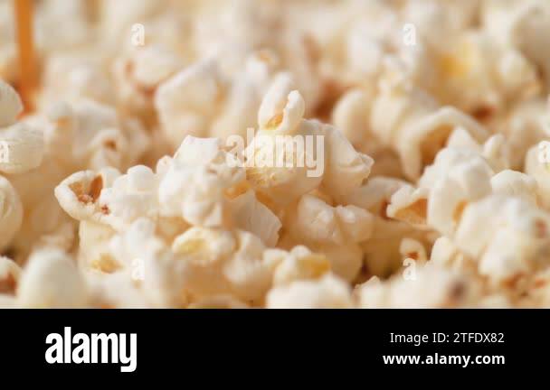 Mixing fresh hot popcorn. Close-up of popcorn production in slow motion ...