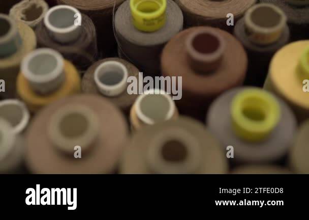 Rows of spools of thread of different colors in a box in the studio ...
