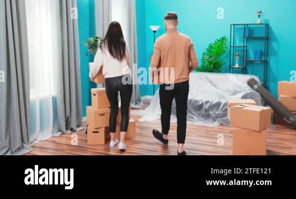 Happy married 20s couple move into new first house bring carton boxes ...