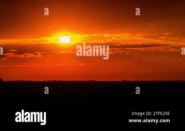 Time lapse bright orange sunset sun sets behind the clouds. The end of ...
