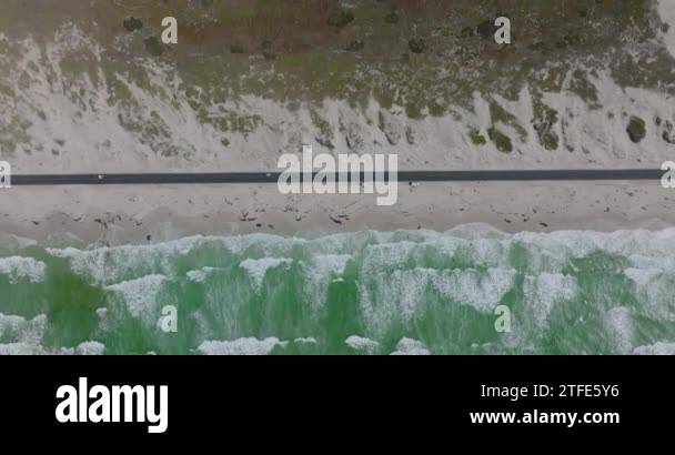 Top down horizontally panning footage of straight coastal road passing ...