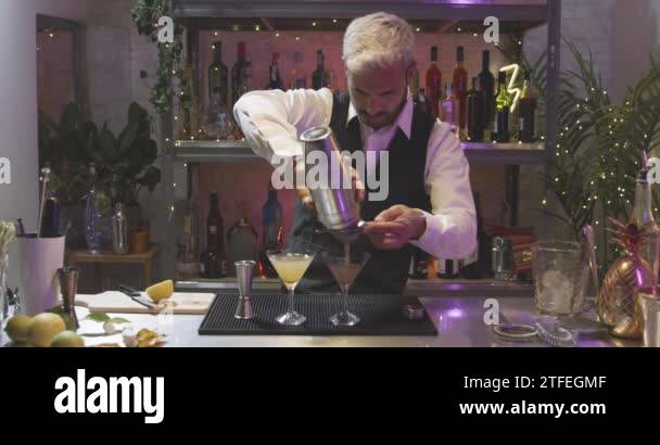 Handsome young professional barman in a white shirt and black apron ...