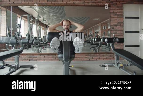 A man is doing exercises for the back and abs on the simulator in the ...
