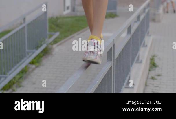 Legs teenager walk along railing courtyard house. He keeps balance in ...